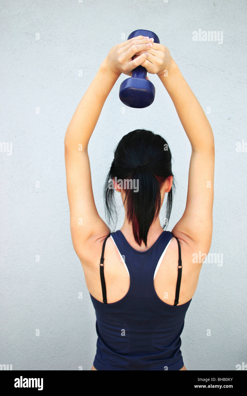 Teenage girl lifts free weights to exercise back muscles Stock Photo ...