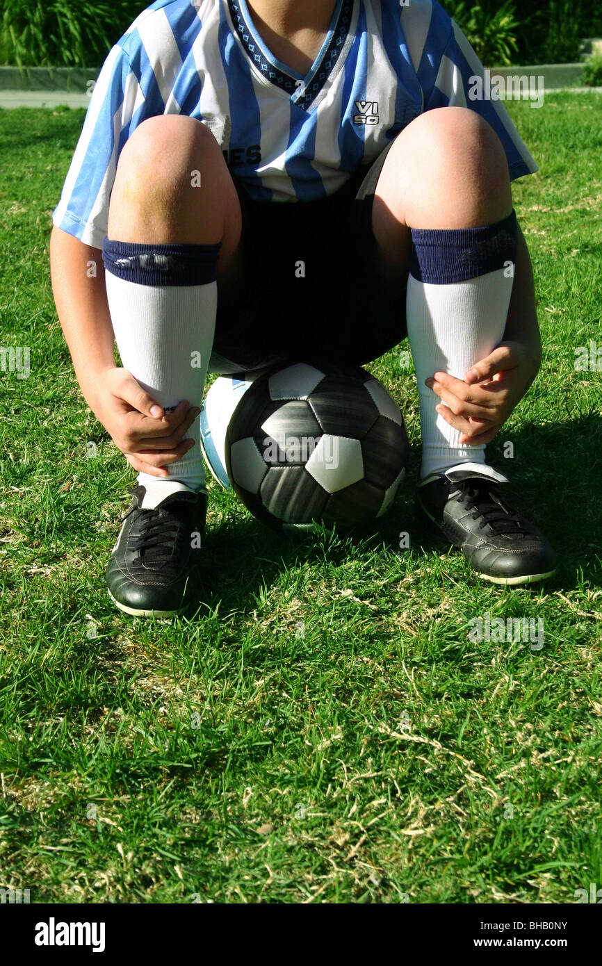 Football player takes a rest by sitting on two footballs Stock Photo ...