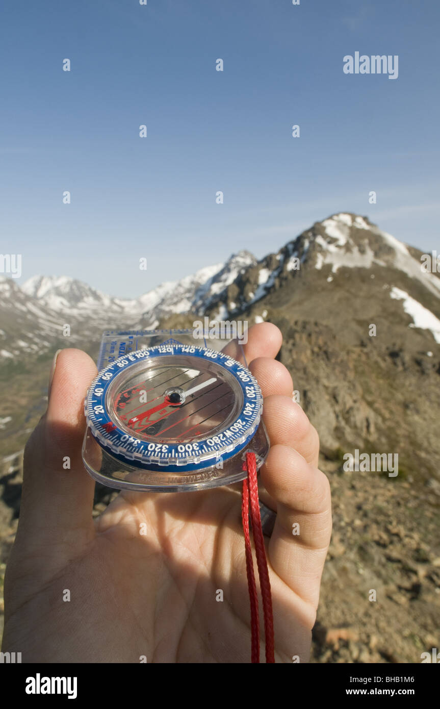 Hiker's hand holding a compass, pointing towards the mountains, Chugach ...