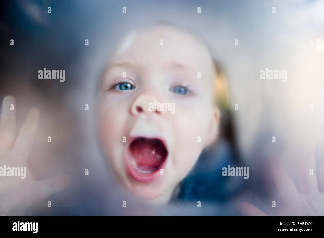 Toddler girl making funny faces out of a steamed up window Stock Photo ...