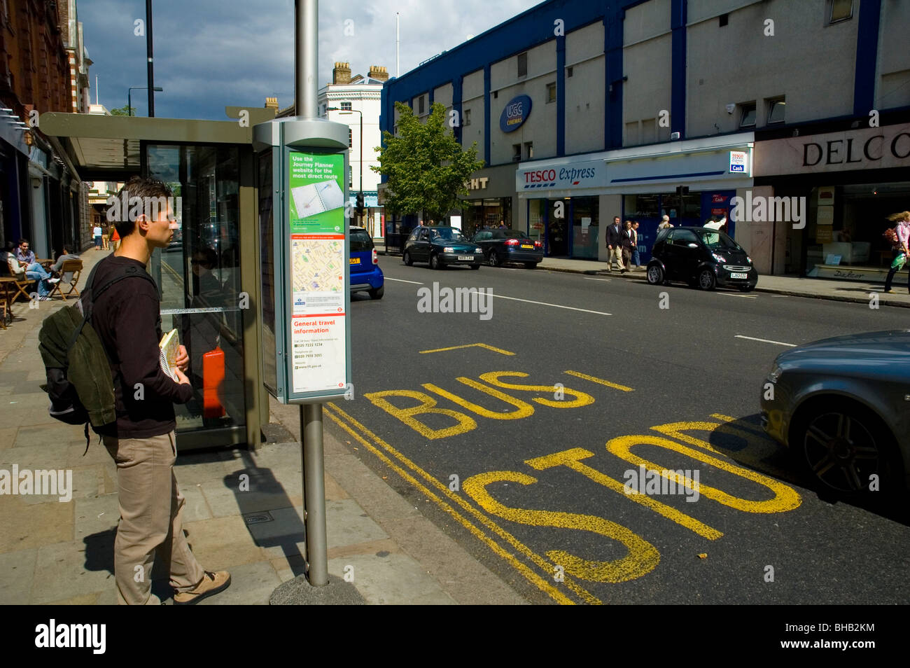 Man at bus stop along Kings Road Kensington London England UK Stock ...
