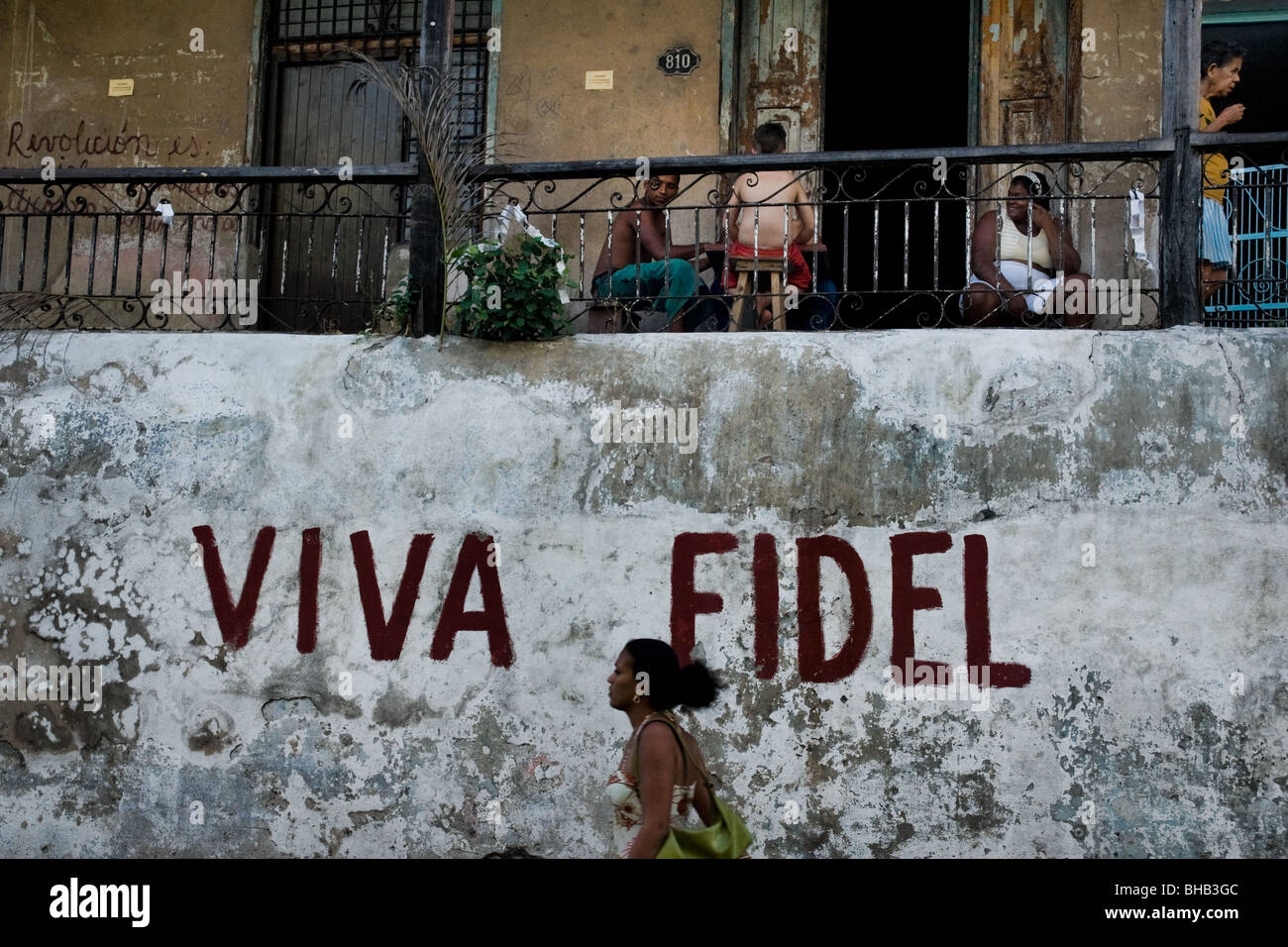 A Cuban woman walking in front of a propaganda writing, celebrating the ...