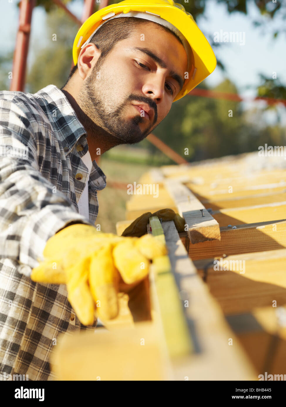 latin american construction worker on house roof with measuring tape ...