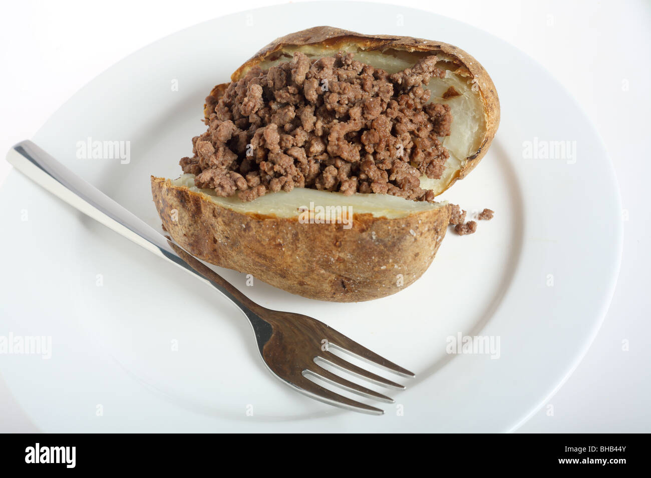 A jacket or baked potato topped with minced beef, with a fork on a ...