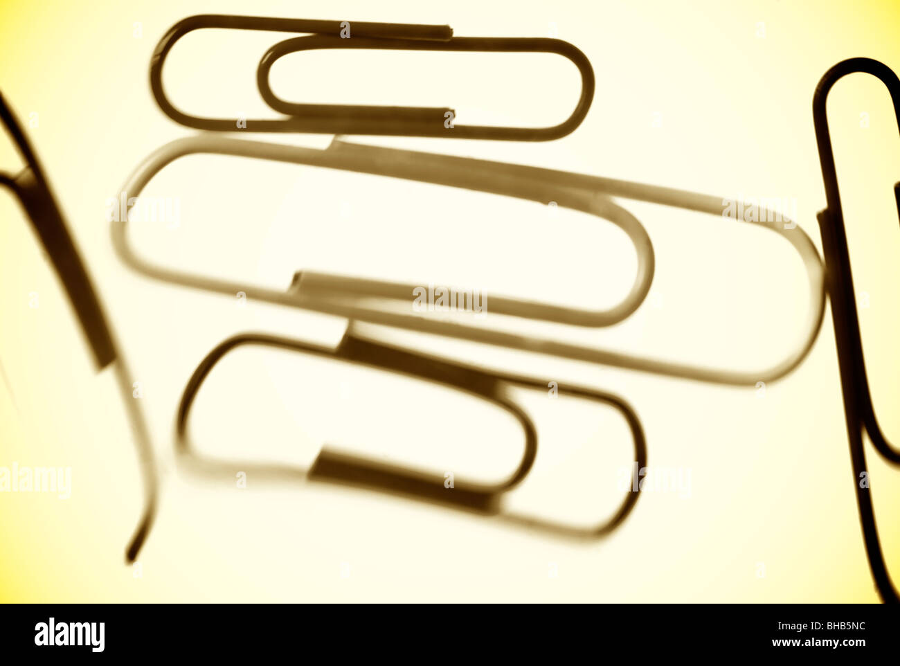 Paper clips on yellow background Stock Photo - Alamy