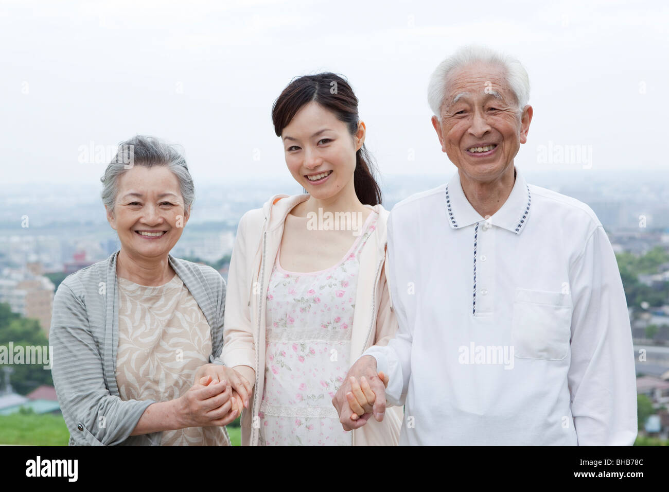 Japan, Tokyo Prefecture, Young woman standing with parents, smiling ...
