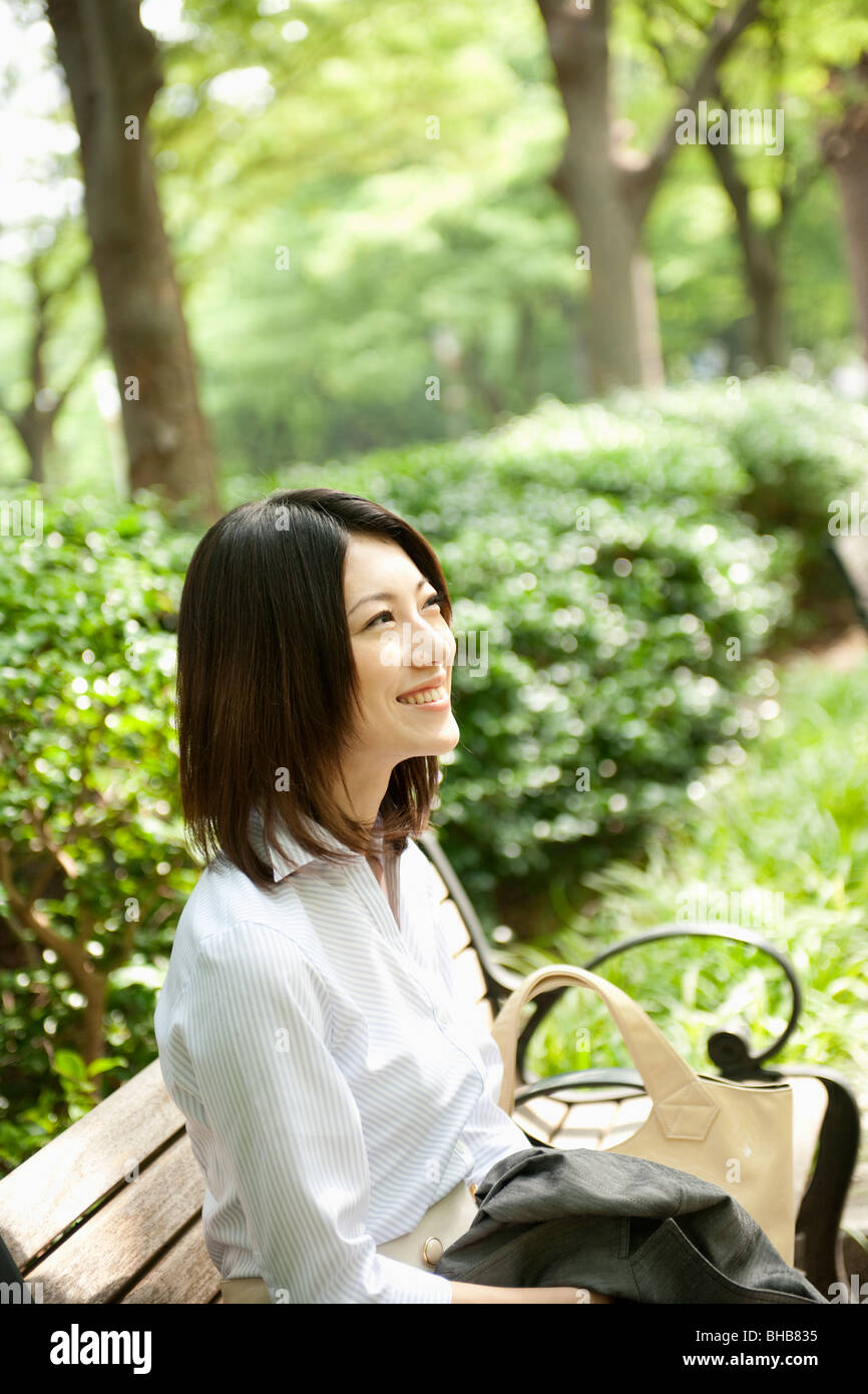 Japan, Osaka Prefecture, Businesswoman sitting on bench, smiling Stock ...