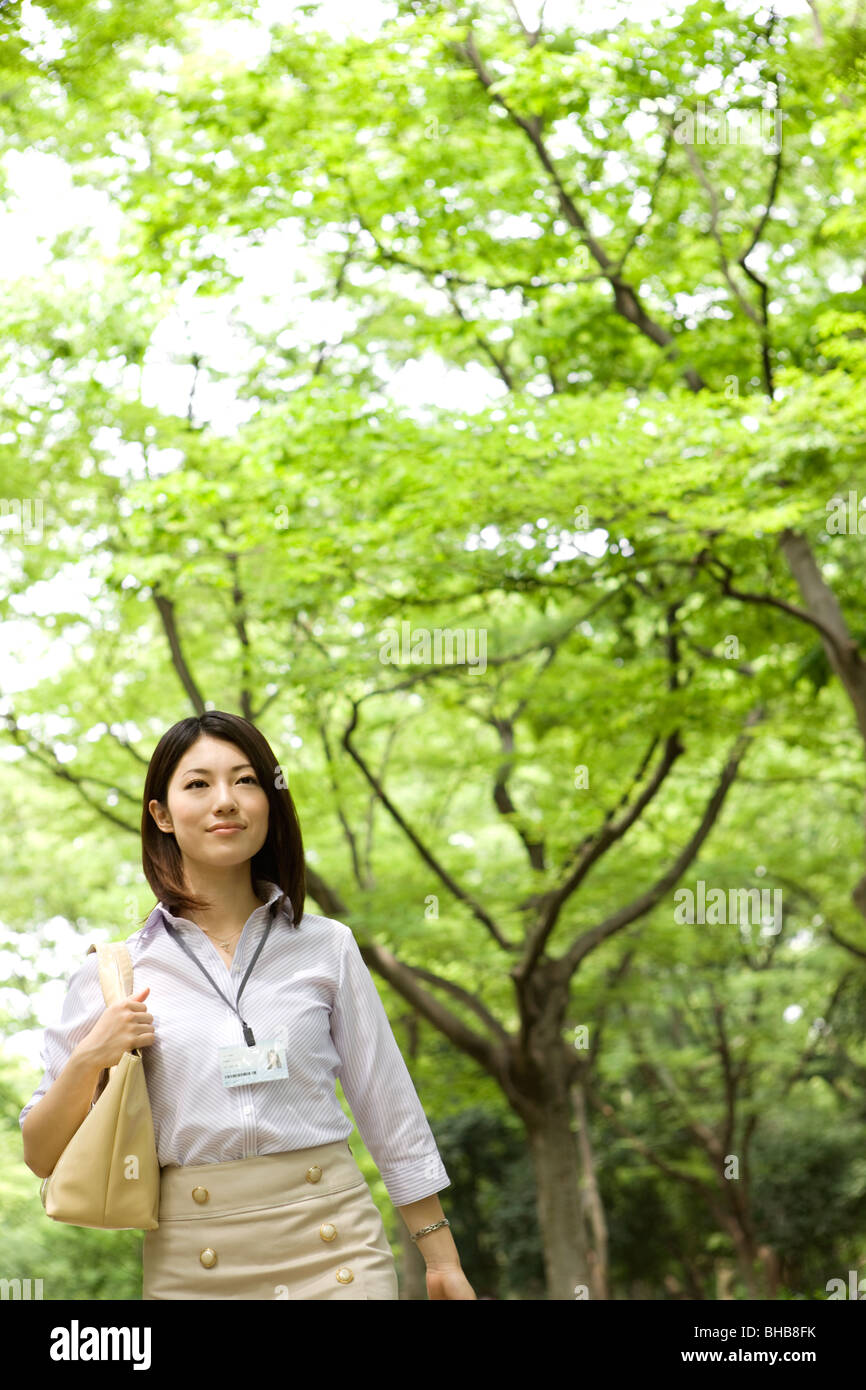 Japan, Osaka Prefecture, Businesswoman walking, smiling, low angle view ...