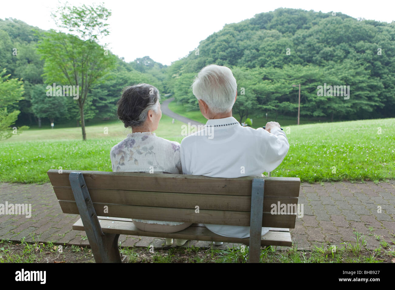 Japan, Tokyo Prefecture, Senior couple sitting on park bench, rear view ...