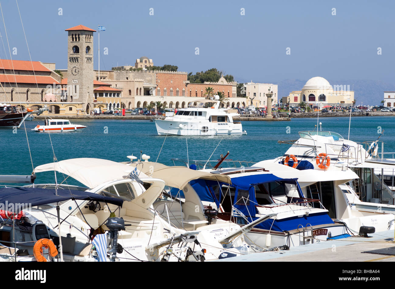 The Mandraki Harbour with a view to the clock tower and the Church of ...