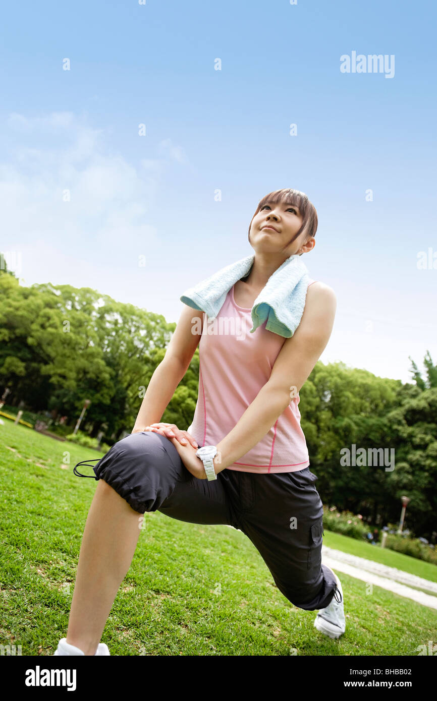 Japan, Osaka Prefecture, Woman stretching legs in park Stock Photo - Alamy
