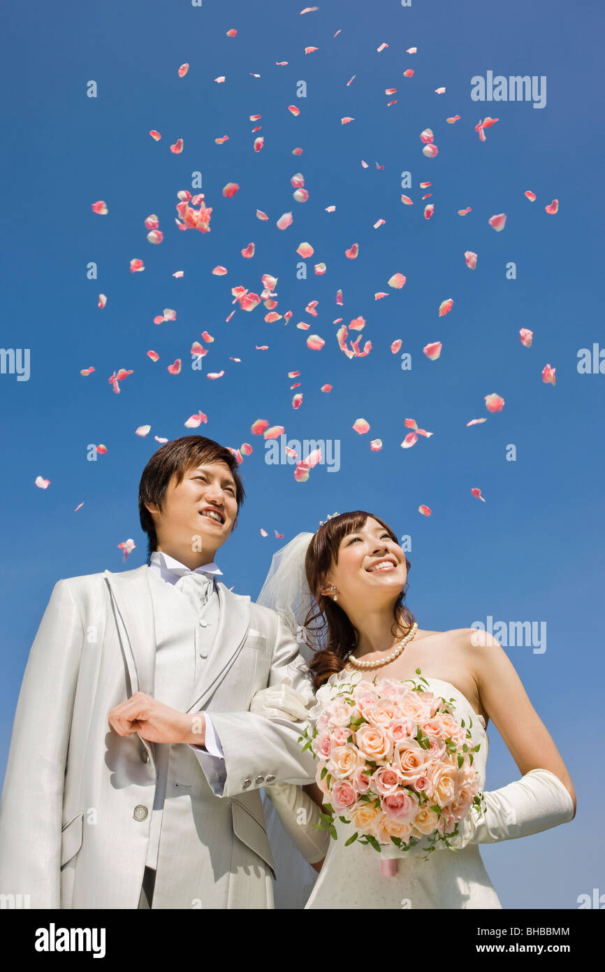 a smiling bride and groom with rose petals falling down on them Stock ...