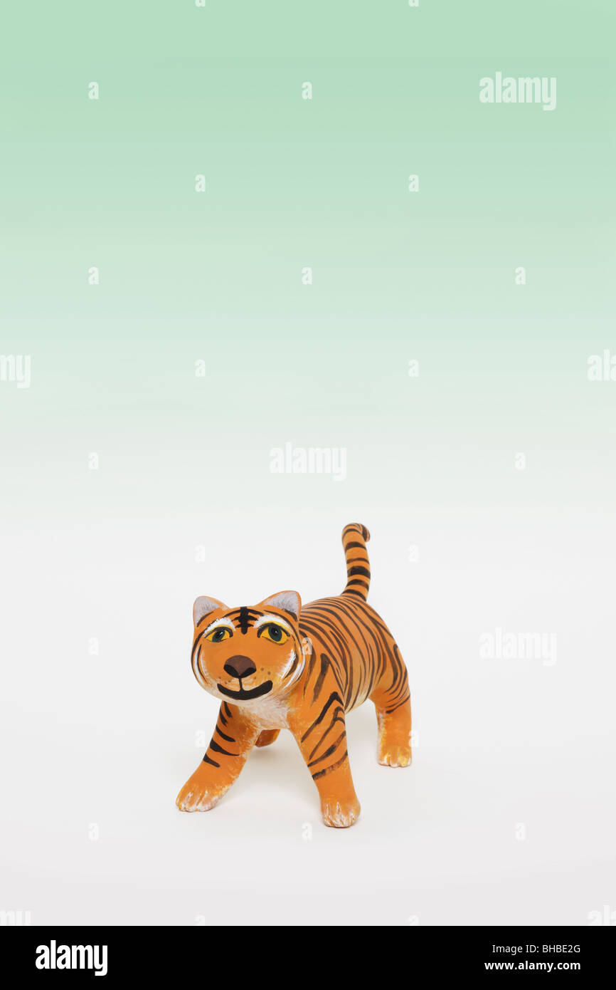 Tiger figurine against green background Stock Photo - Alamy