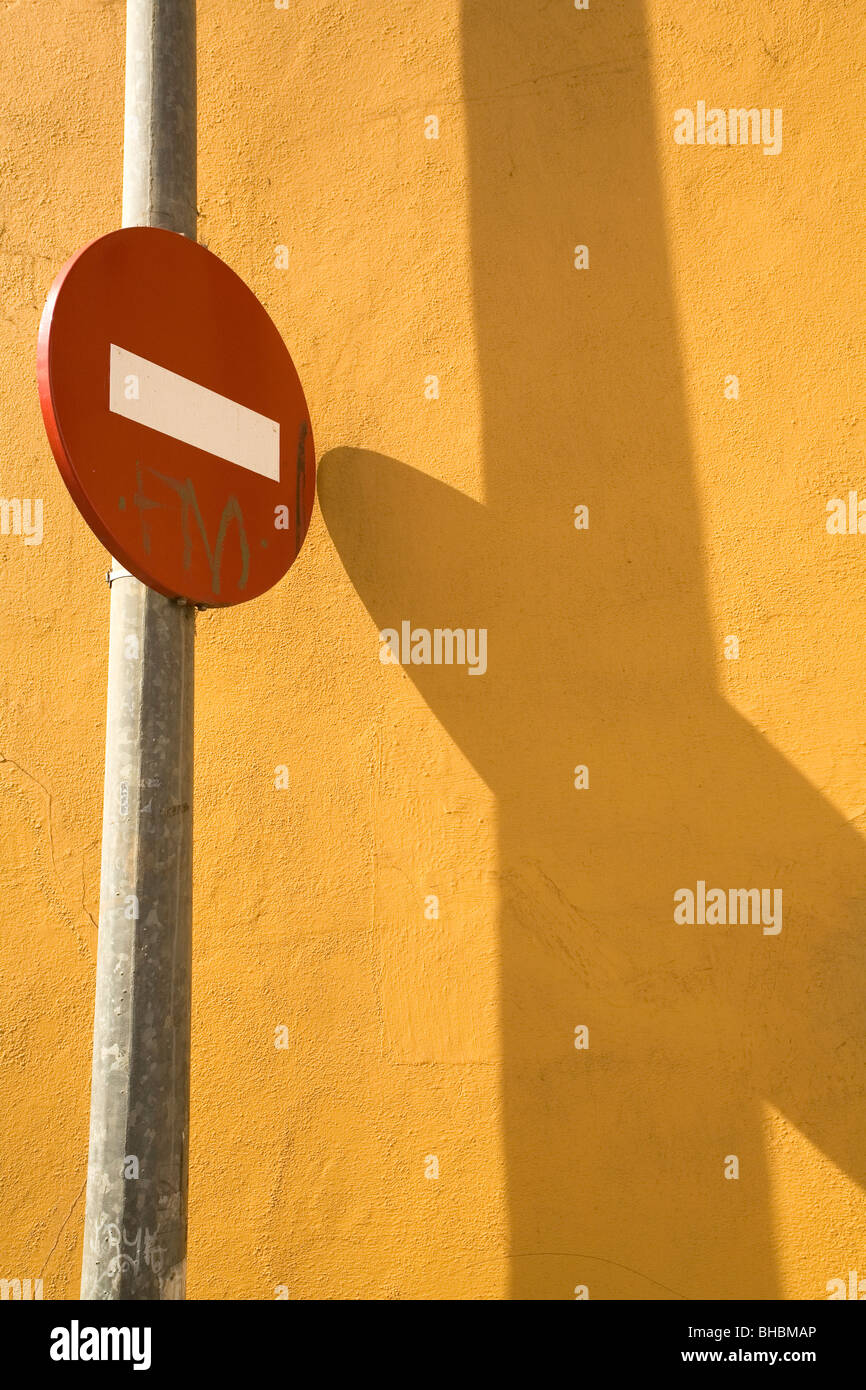 A red No Entry street sign stands next to an orange wall. The sign ...