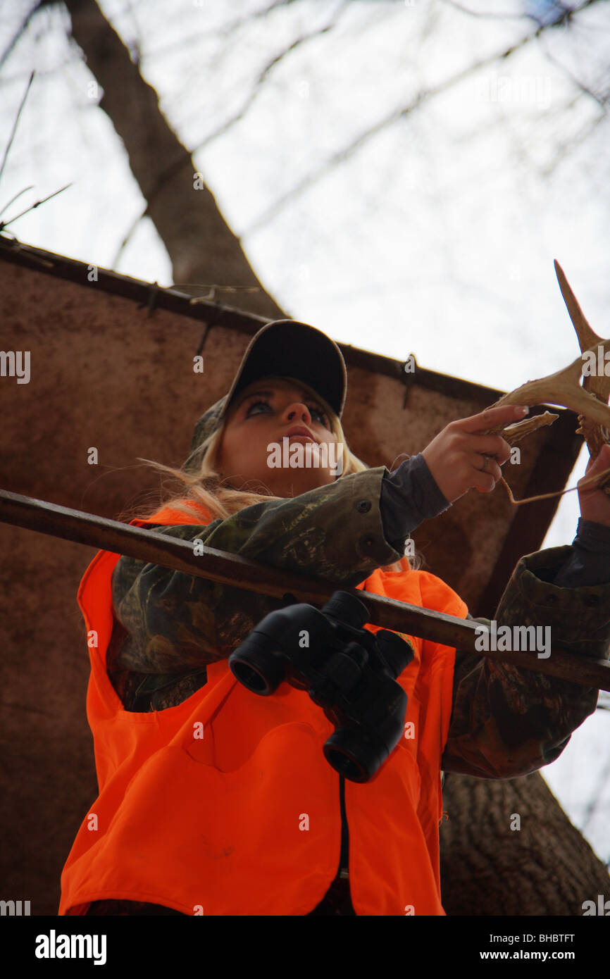 YOUNG WOMAN 21 Y.O. FEMALE HUNTER IN A TREE STAND HOLDING RIFLE ORANGE ...