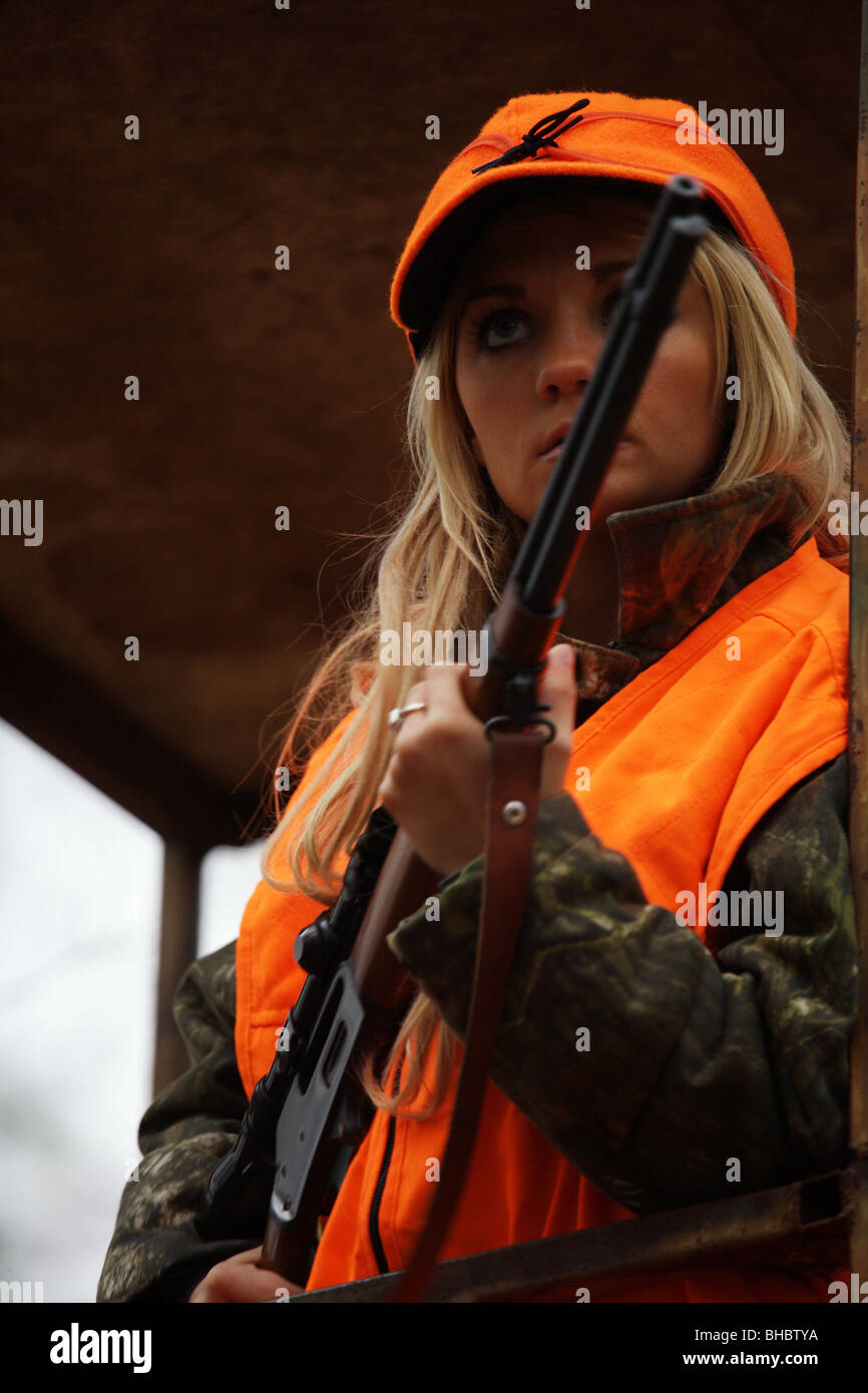 YOUNG WOMAN 21 Y.O. FEMALE HUNTER IN A TREE STAND HOLDING RIFLE ORANGE ...