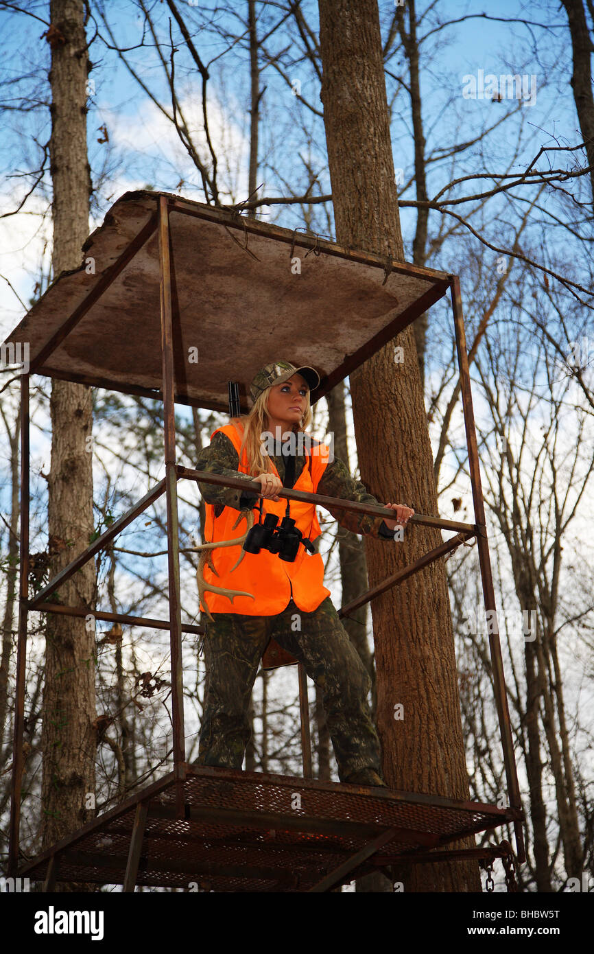 YOUNG WOMAN 21 Y.O. FEMALE HUNTER IN A TREE STAND HOLDING RIFLE ORANGE ...