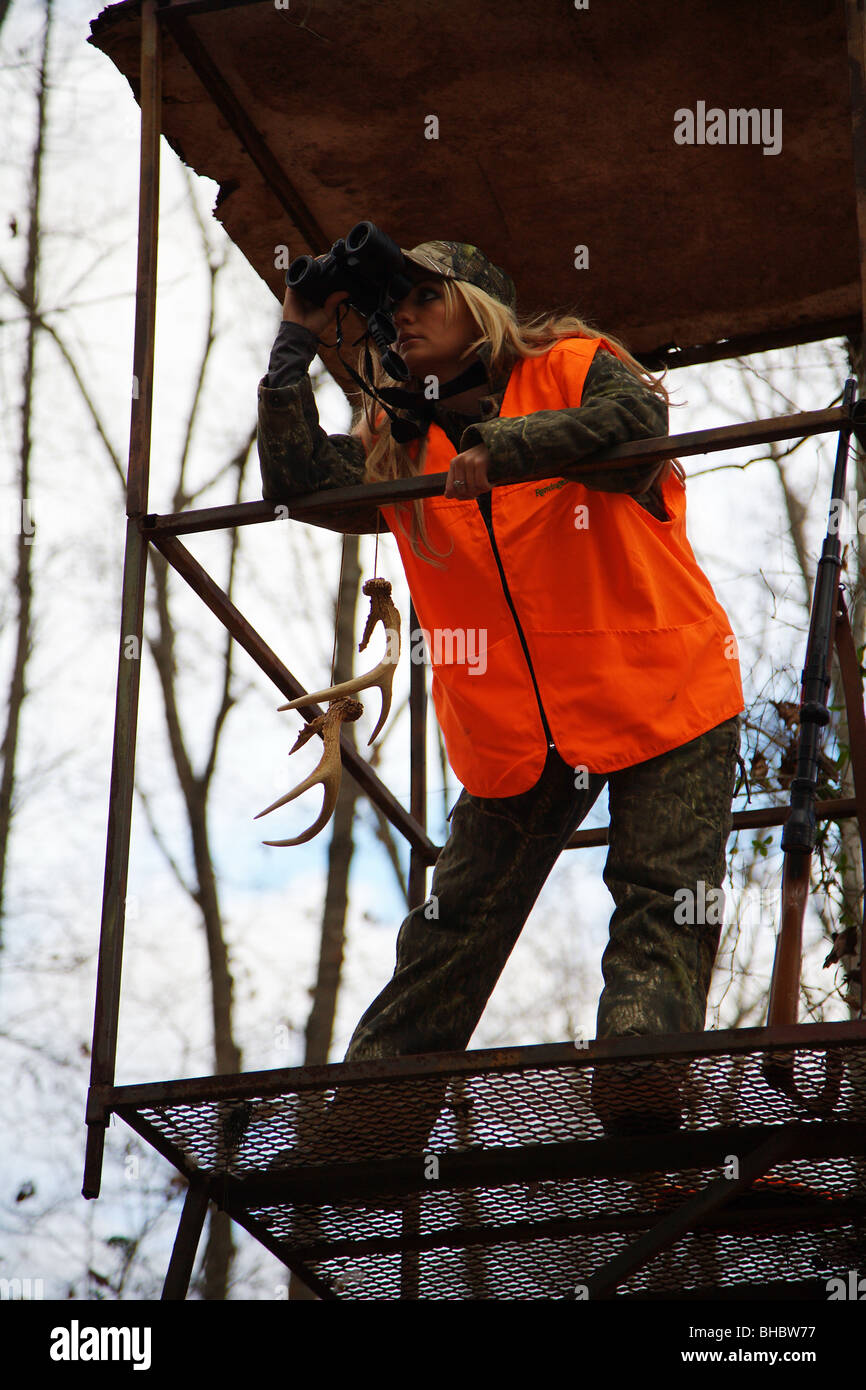 YOUNG WOMAN 21 Y.O. FEMALE HUNTER IN A TREE STAND HOLDING RIFLE ORANGE ...