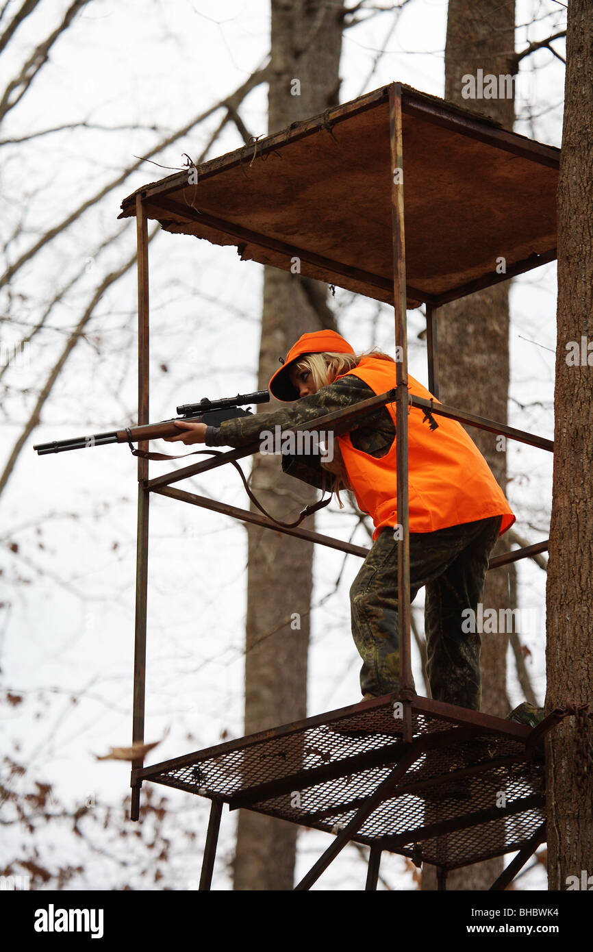YOUNG WOMAN 21 Y.O. FEMALE HUNTER IN A TREE STAND HOLDING RIFLE ORANGE ...