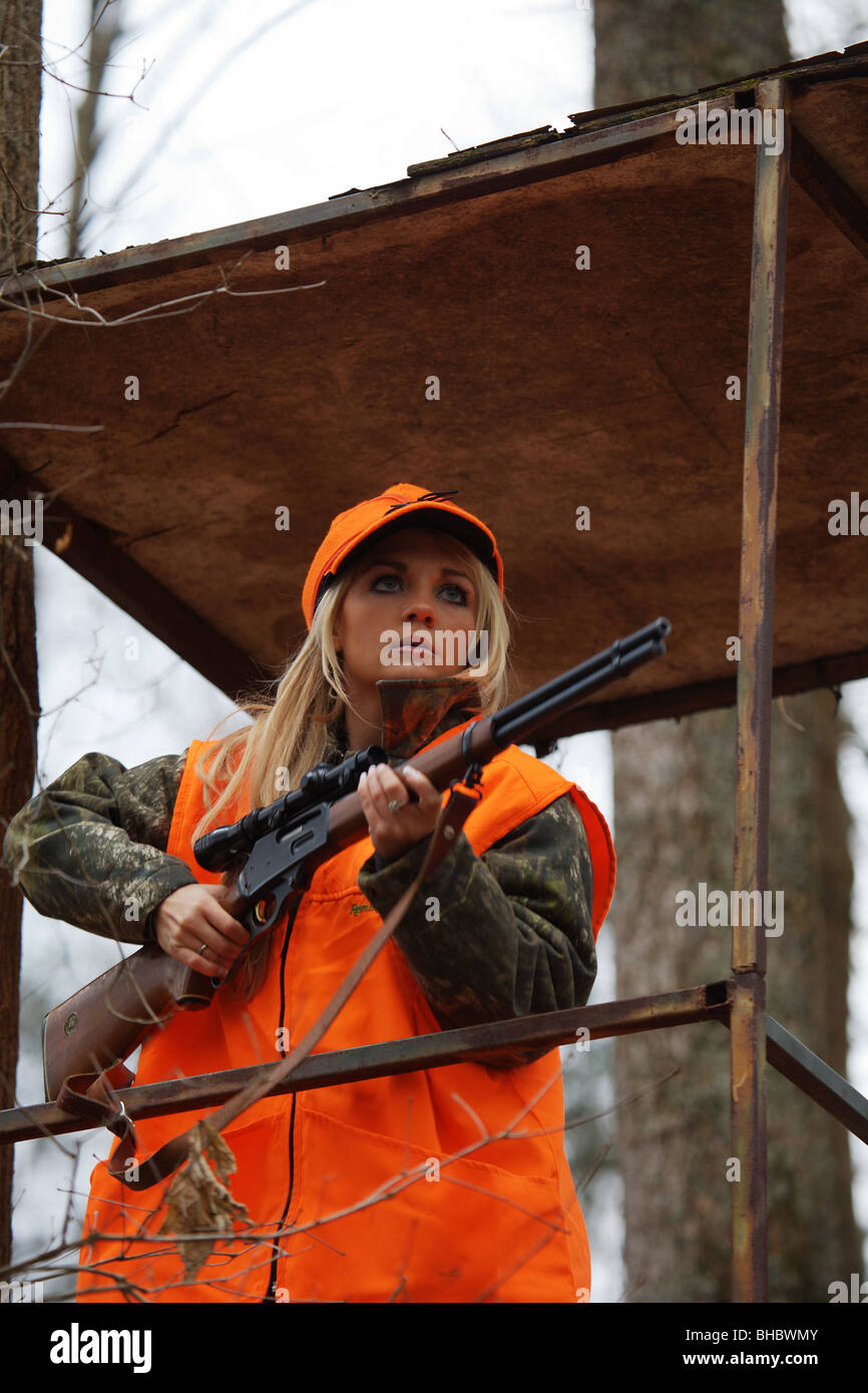 YOUNG WOMAN 21 Y.O. FEMALE HUNTER IN A TREE STAND HOLDING RIFLE ORANGE ...