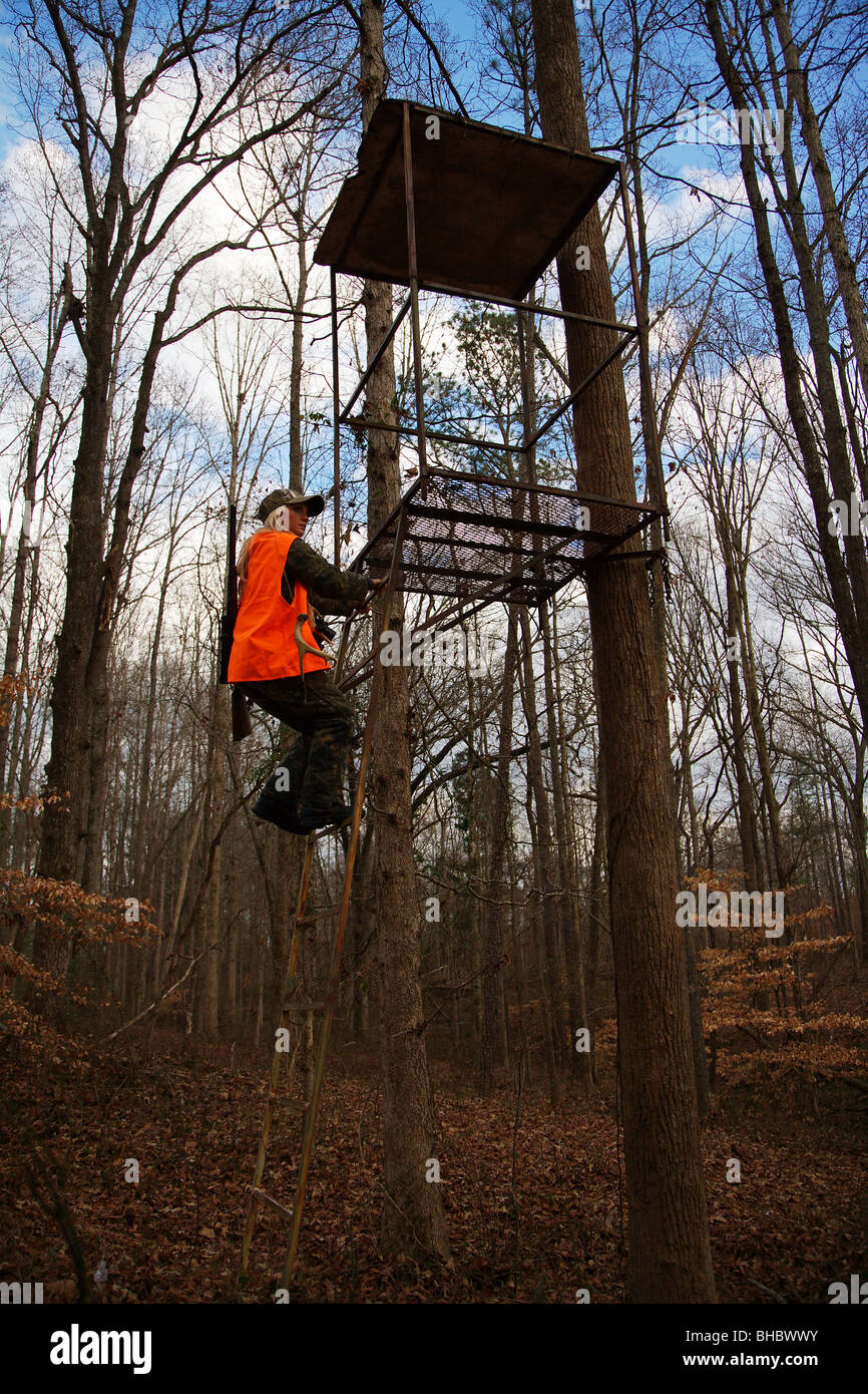 YOUNG WOMAN 21 Y.O. FEMALE HUNTER IN A TREE STAND HOLDING RIFLE ORANGE ...
