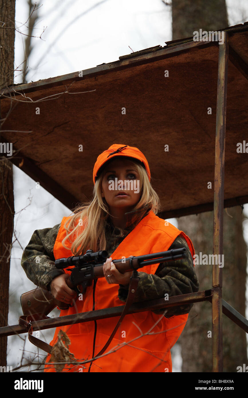 YOUNG WOMAN 21 Y.O. FEMALE HUNTER IN A TREE STAND HOLDING RIFLE ORANGE ...