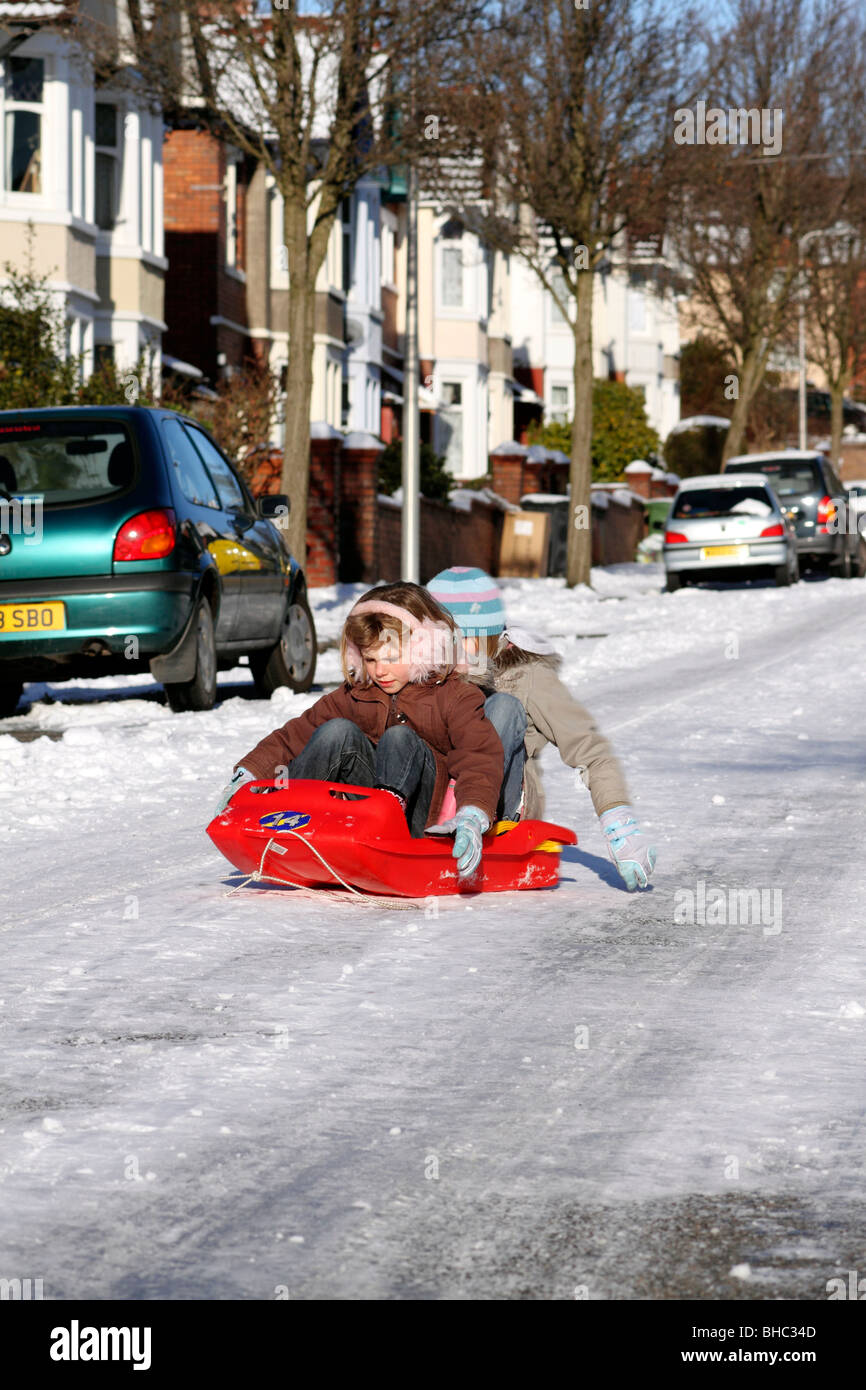 two girls in a double sledge having fun in the snow Stock Photo - Alamy