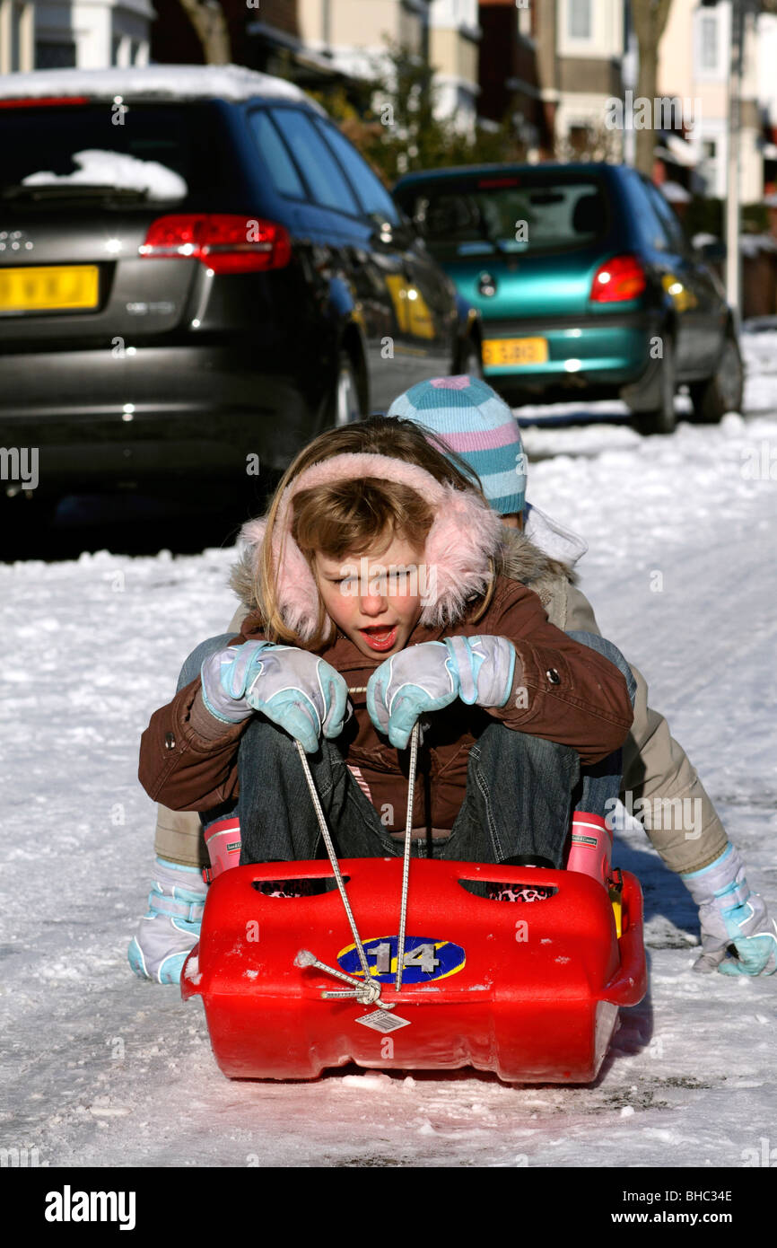 two girls in a double sledge having fun in the snow Stock Photo - Alamy