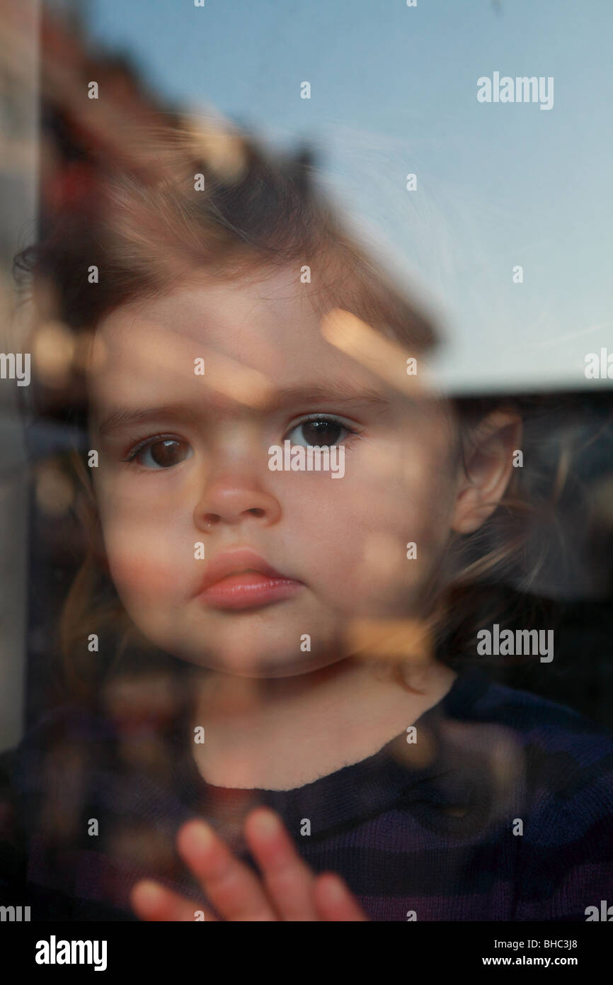 A twenty months old baby looking up through a window with reflection ...