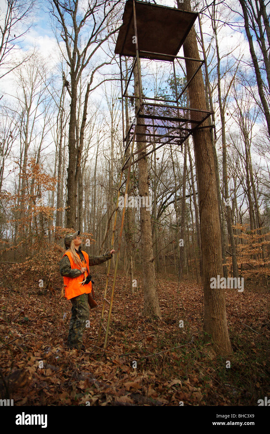 YOUNG WOMAN 21 Y.O. FEMALE HUNTER IN A TREE STAND HOLDING RIFLE ORANGE ...