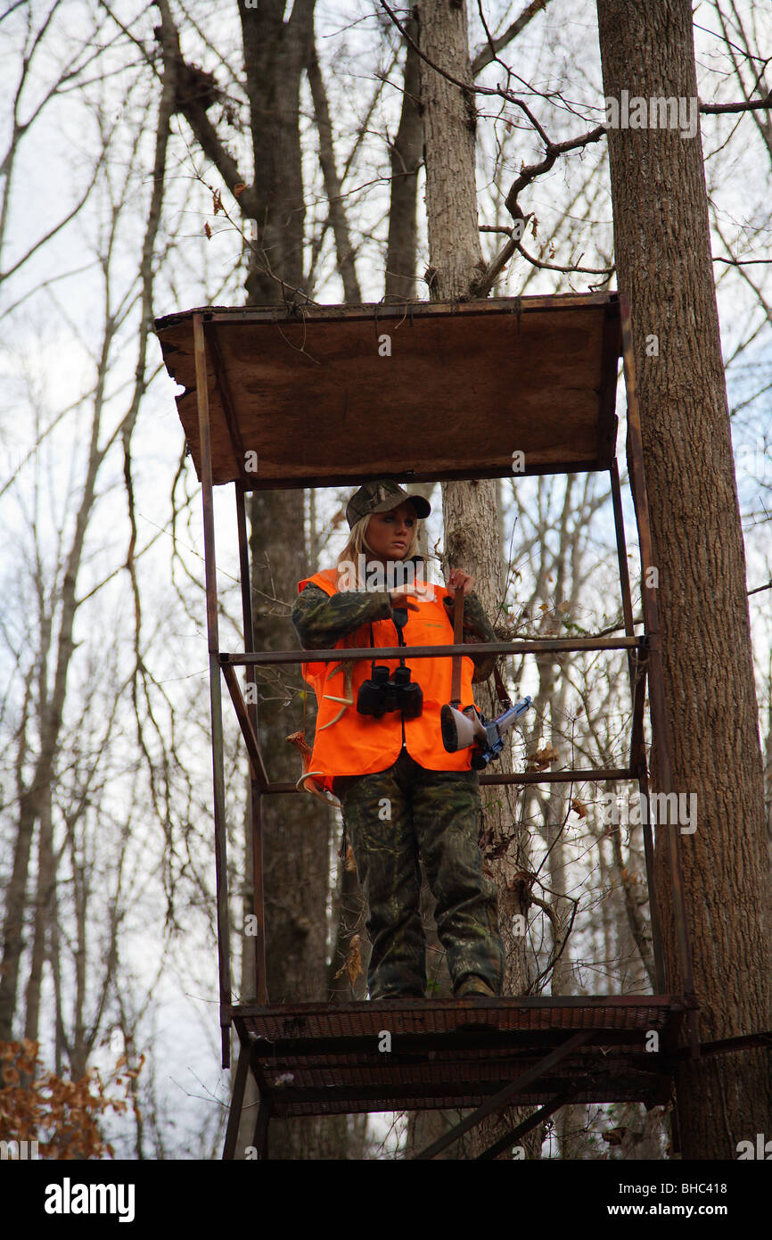 YOUNG WOMAN 21 Y.O. FEMALE HUNTER IN A TREE STAND HOLDING RIFLE ORANGE ...