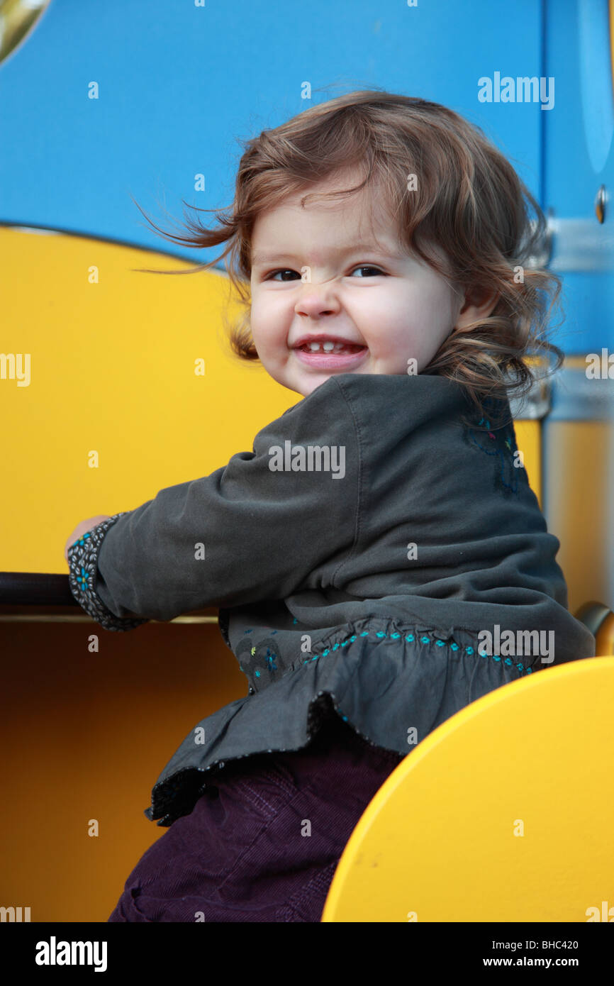 A twenty months old baby girl playing on a slide into a public garden ...