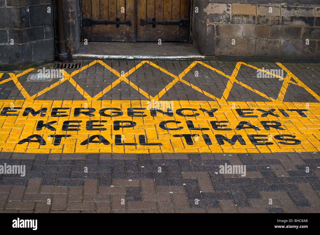 Sign painted on pavement outside an old stone public building EMERGENCY ...