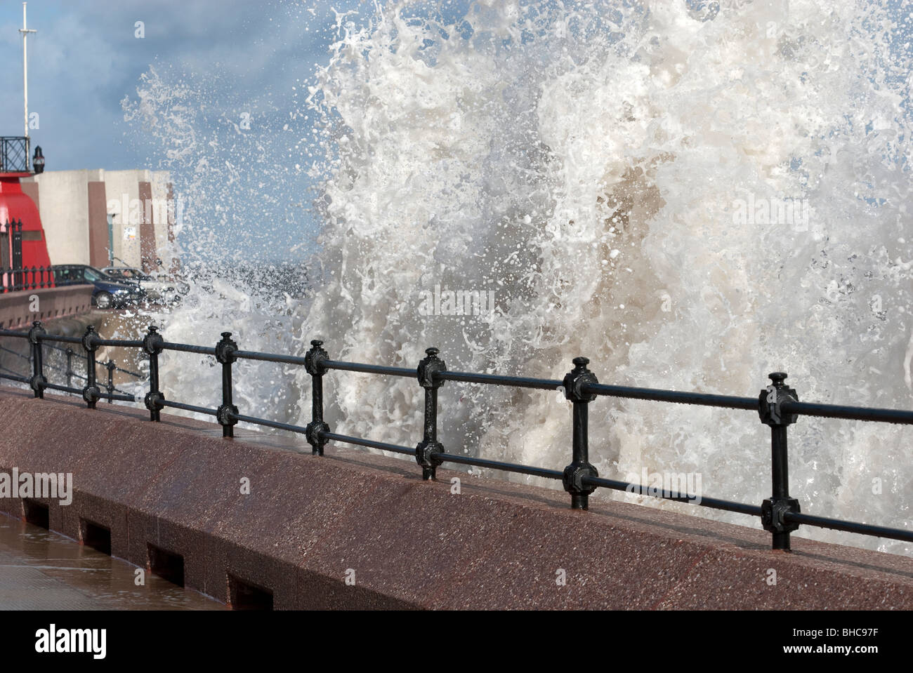 Waves crashing over sea wall railings Stock Photo - Alamy