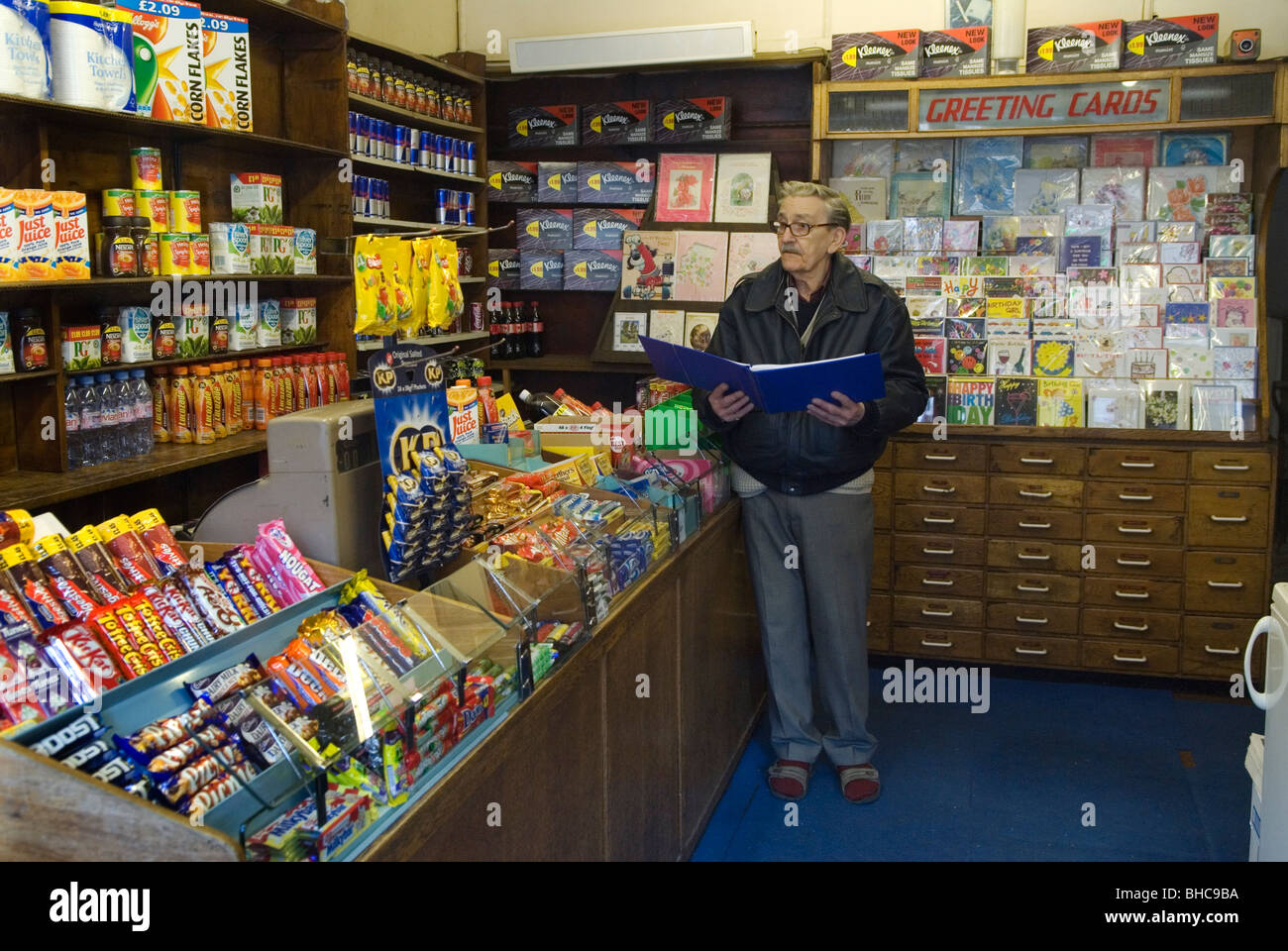 Corner shop UK. Elderly owner stock taking, selling sweets, birthday ...