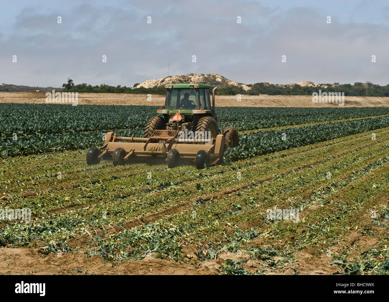 Farmer in tractor with agriculture machinery harvesting and ploughing ...