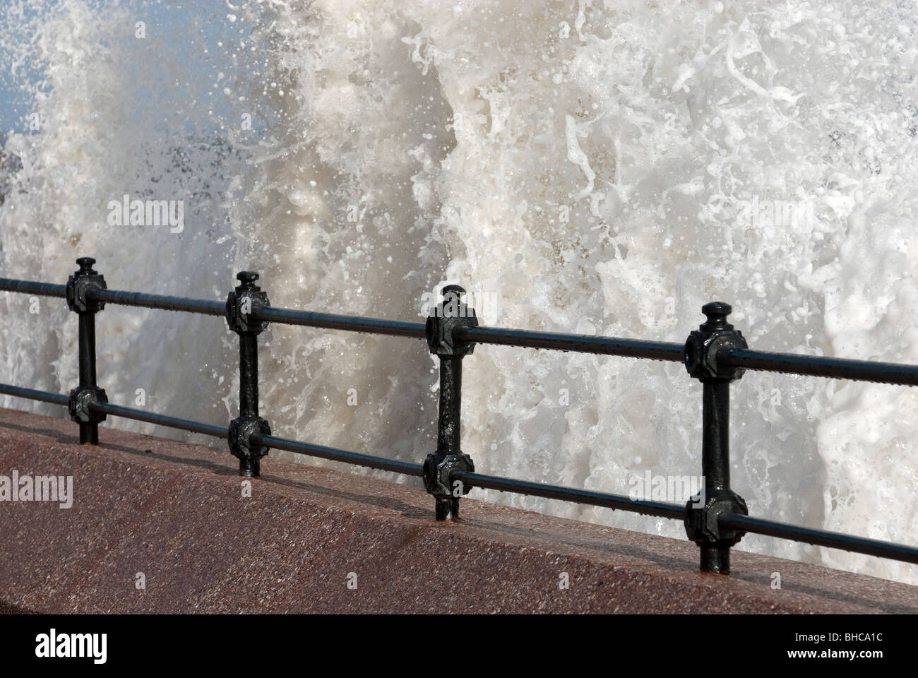 Waves crashing over sea wall railings Stock Photo - Alamy