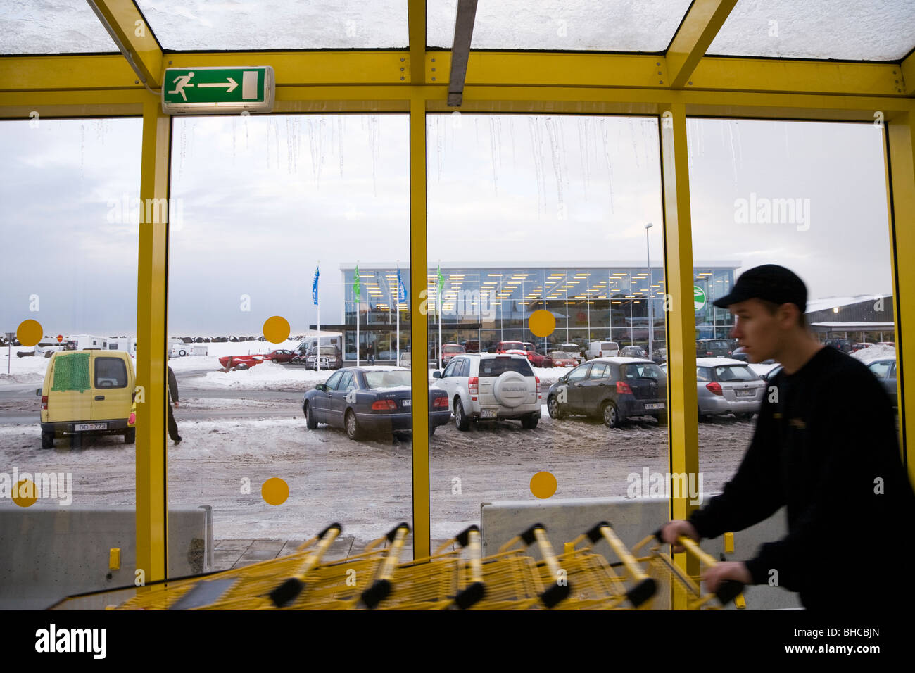 Young man rounds-up shopping trolleys. Bonus supermarket, Reykjavik ...