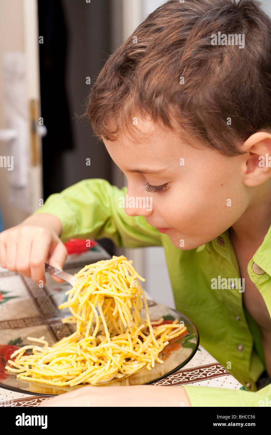 Cute kid eating delicious pasta, indoor shot Stock Photo - Alamy