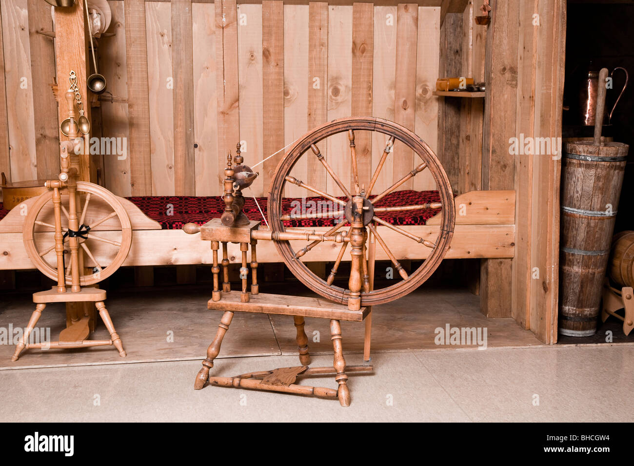 Old spinning wheels, a butter churn and a bed inside a typical living ...