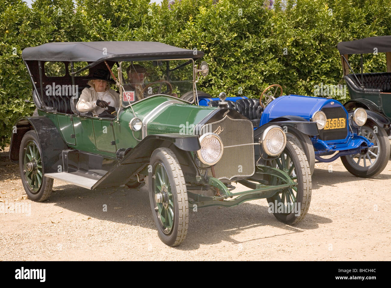 Couple dressed in old-fashioned clothing, in their antique car at rally ...