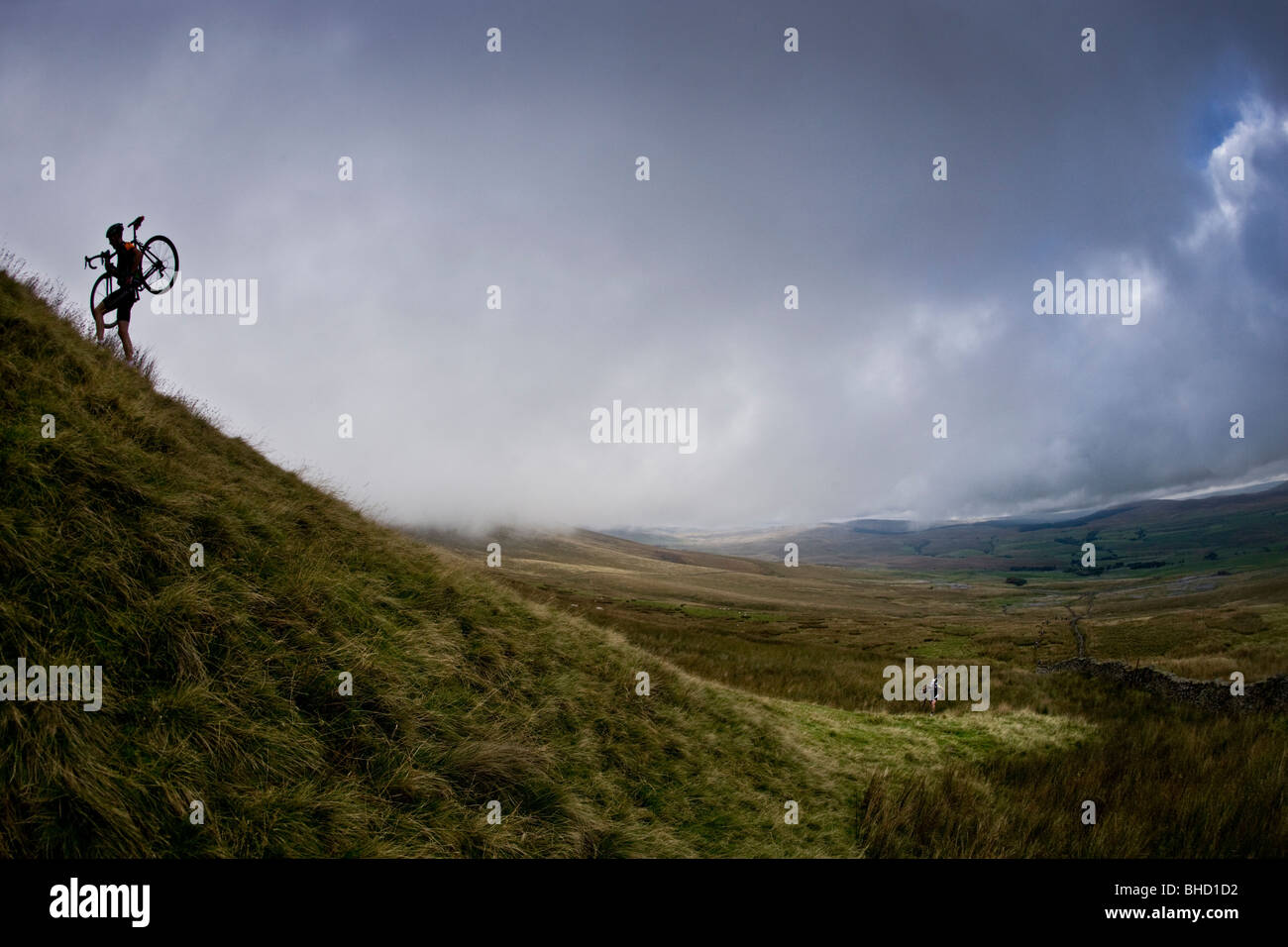 Cyclists carry their bicycles up a mountain during the Three Peaks ...