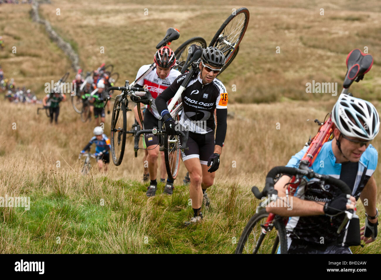 Crowd of cyclists carry their bicycles up a mountain during the Three ...