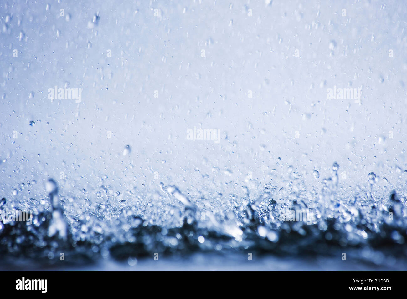 Drops creating splashes in water Stock Photo - Alamy