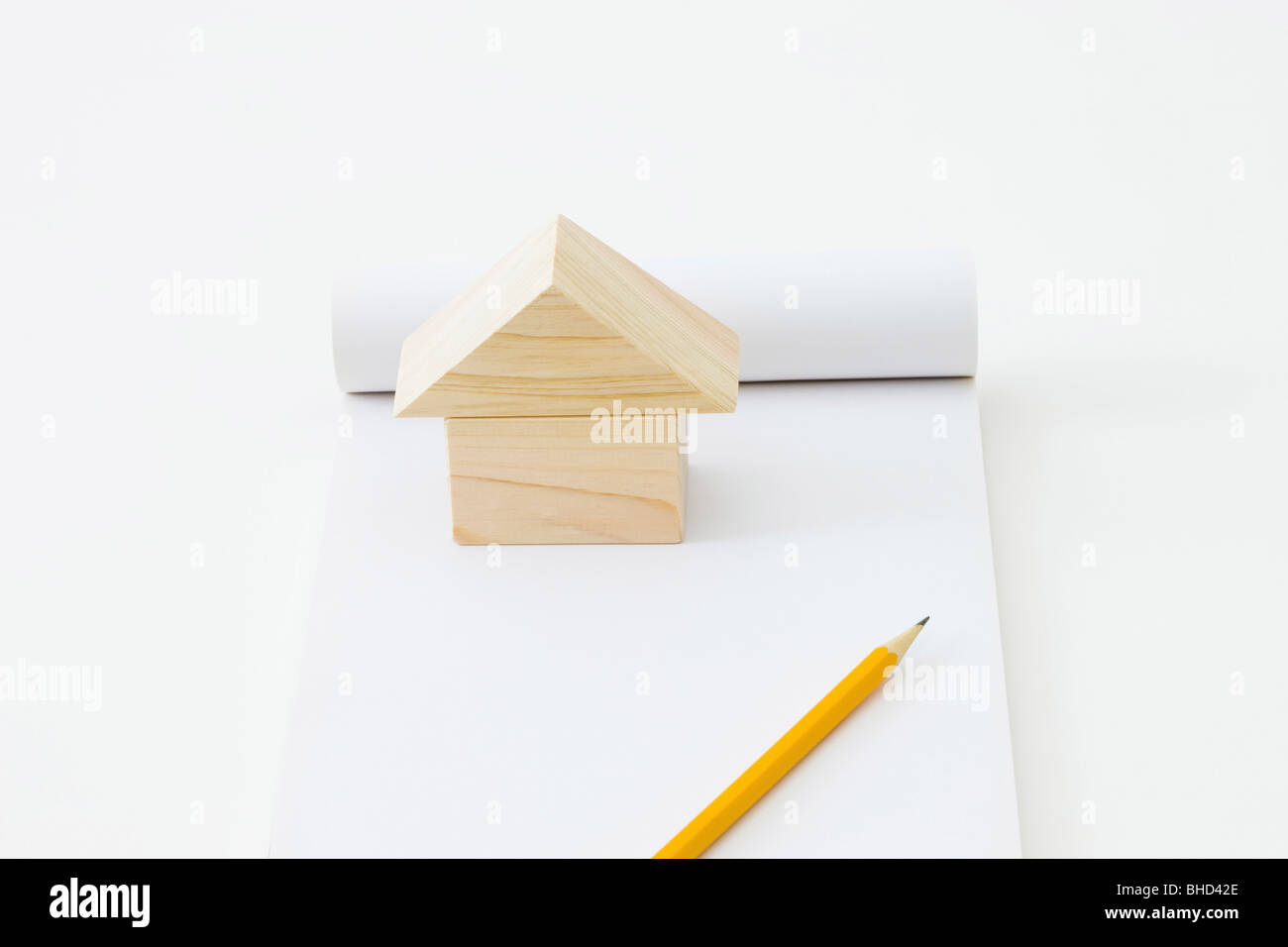 Wooden block house and pencil on blank notepad Stock Photo - Alamy