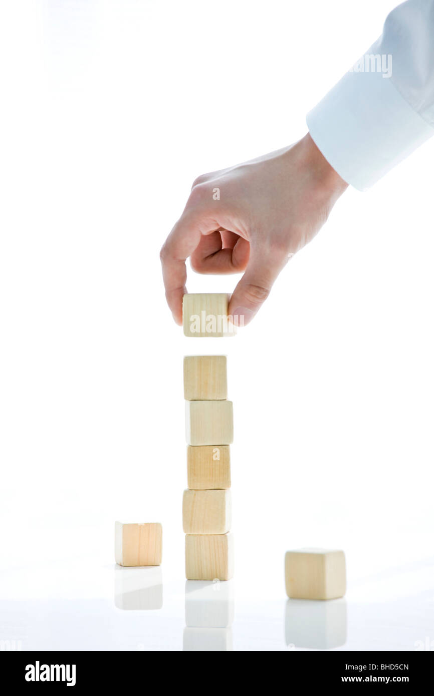 Man building a stack of building blocks Stock Photo - Alamy
