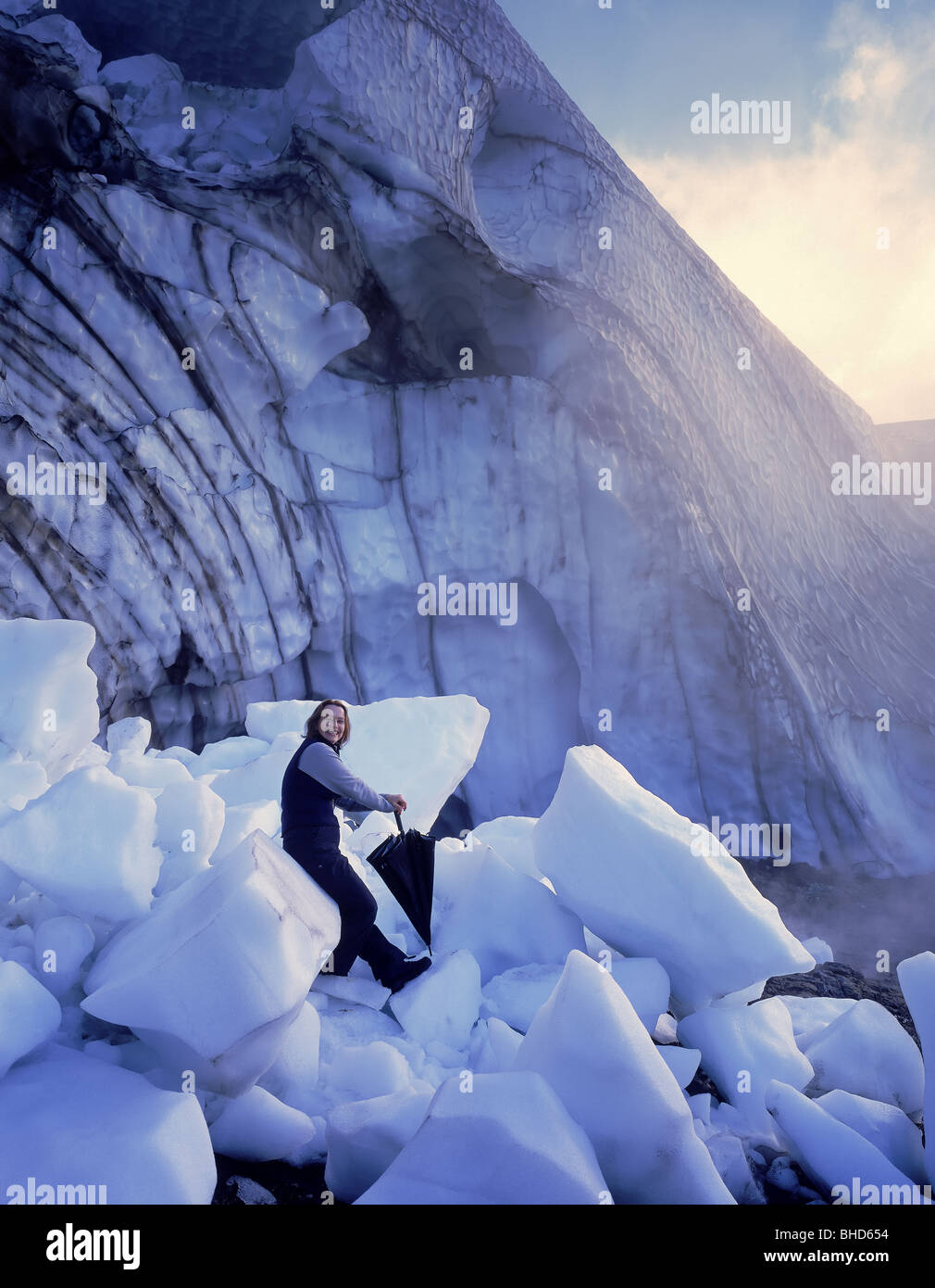 Woman sitting on ice in front of glacial Ice Cave, Hrafntinnusker ...