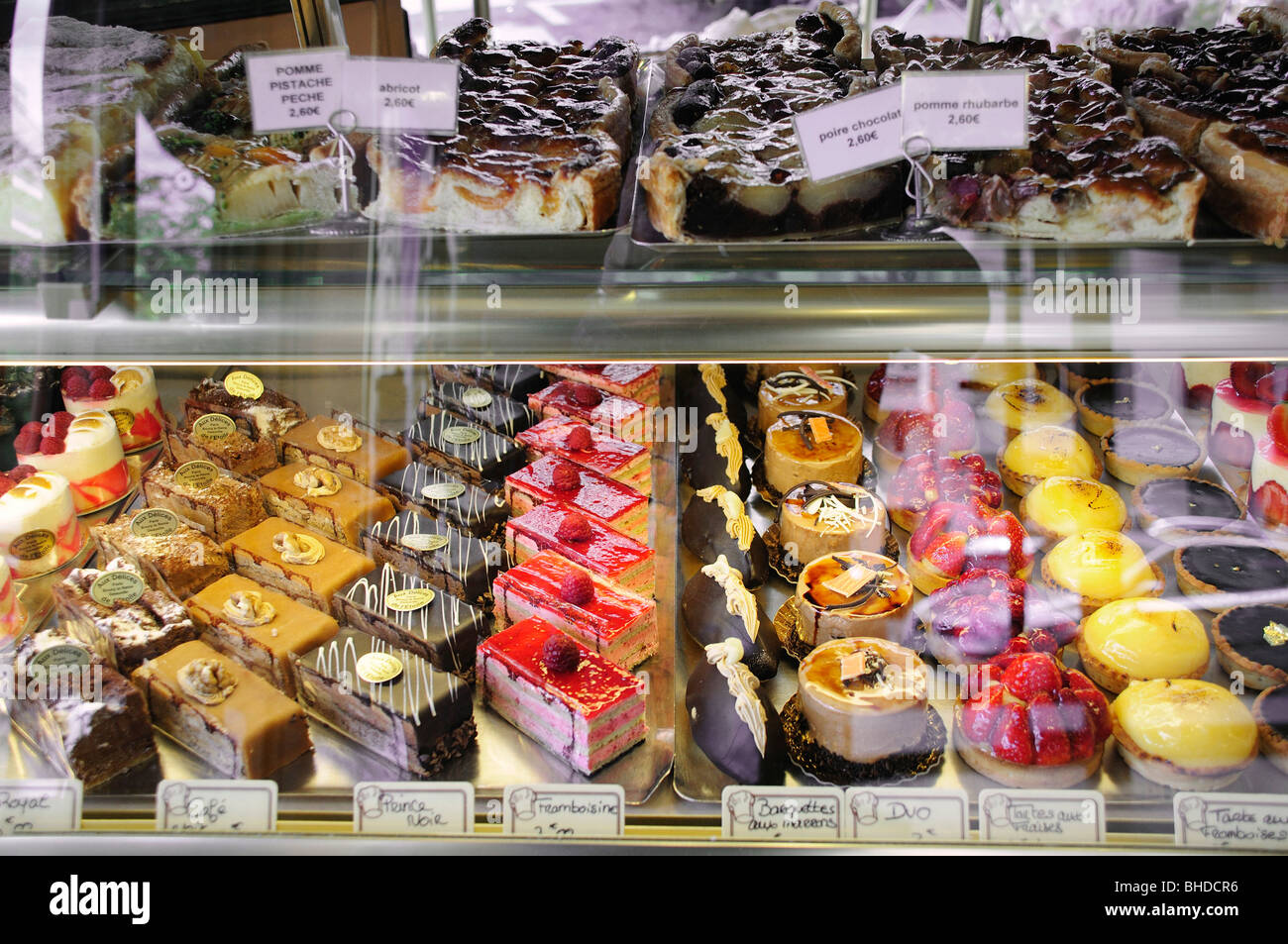 Selection of French cakes behind glass counter Stock Photo - Alamy