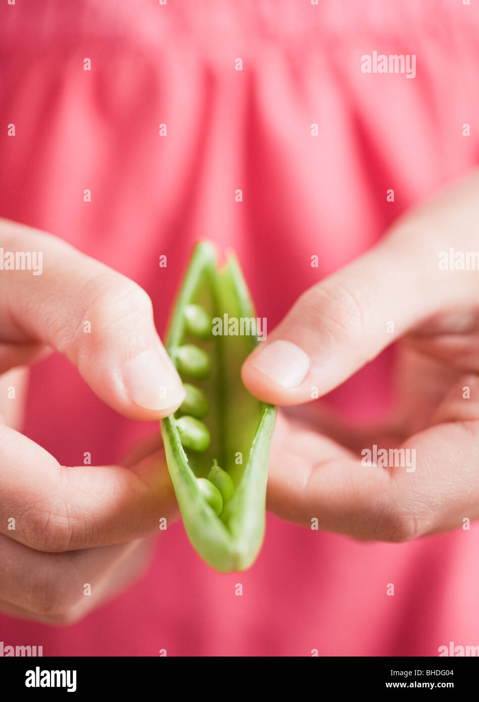 Mixed race girl opening pea pod Stock Photo - Alamy