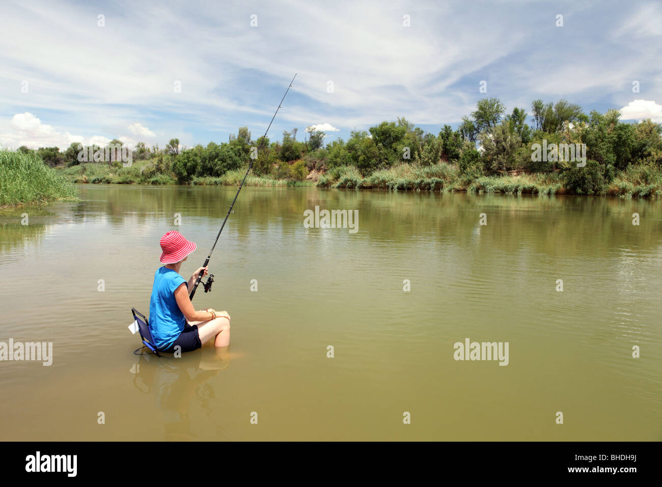A woman sits fishing in the wtaer of the Orange River near Upington ...